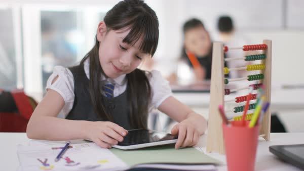 Young school children in class with little girl using abacus & computer ...