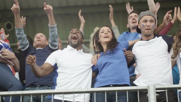 Excited fans with US flag in sports crowd, celebrating & cheering on ...