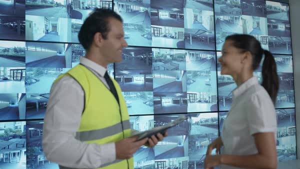 Portrait smiling security officers in system control room with wall of ...