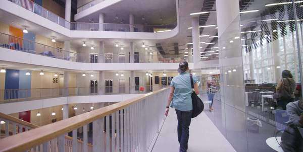 Diverse group of students walking through large contemporary university ...
