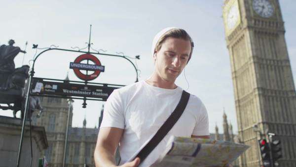 Casual young man looking at London map and trying to find his way ...