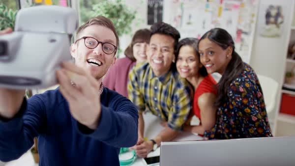 Creative business team in modern office pose for selfie with polaroid ...