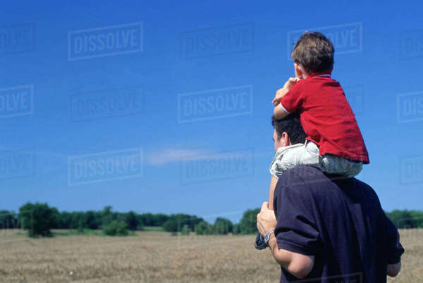 Boy Sitting On Father's Shoulders - Stock Photo - Dissolve