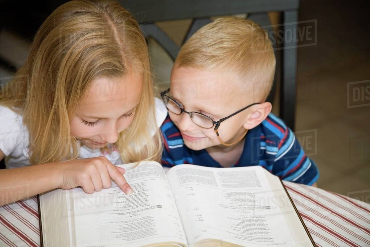 Boy And Girl Reading The Bible Together - Stock Photo - Dissolve