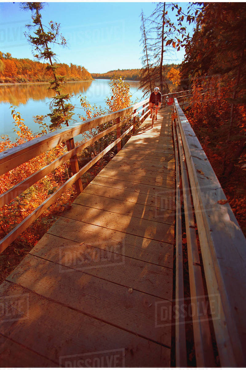 Cyclist On Wooden Pathway By River - Royalty-free Stock Photo | Dissolve