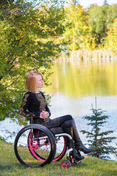 Young disabled woman in a wheelchair in a city park in autumn; Edmonton ...