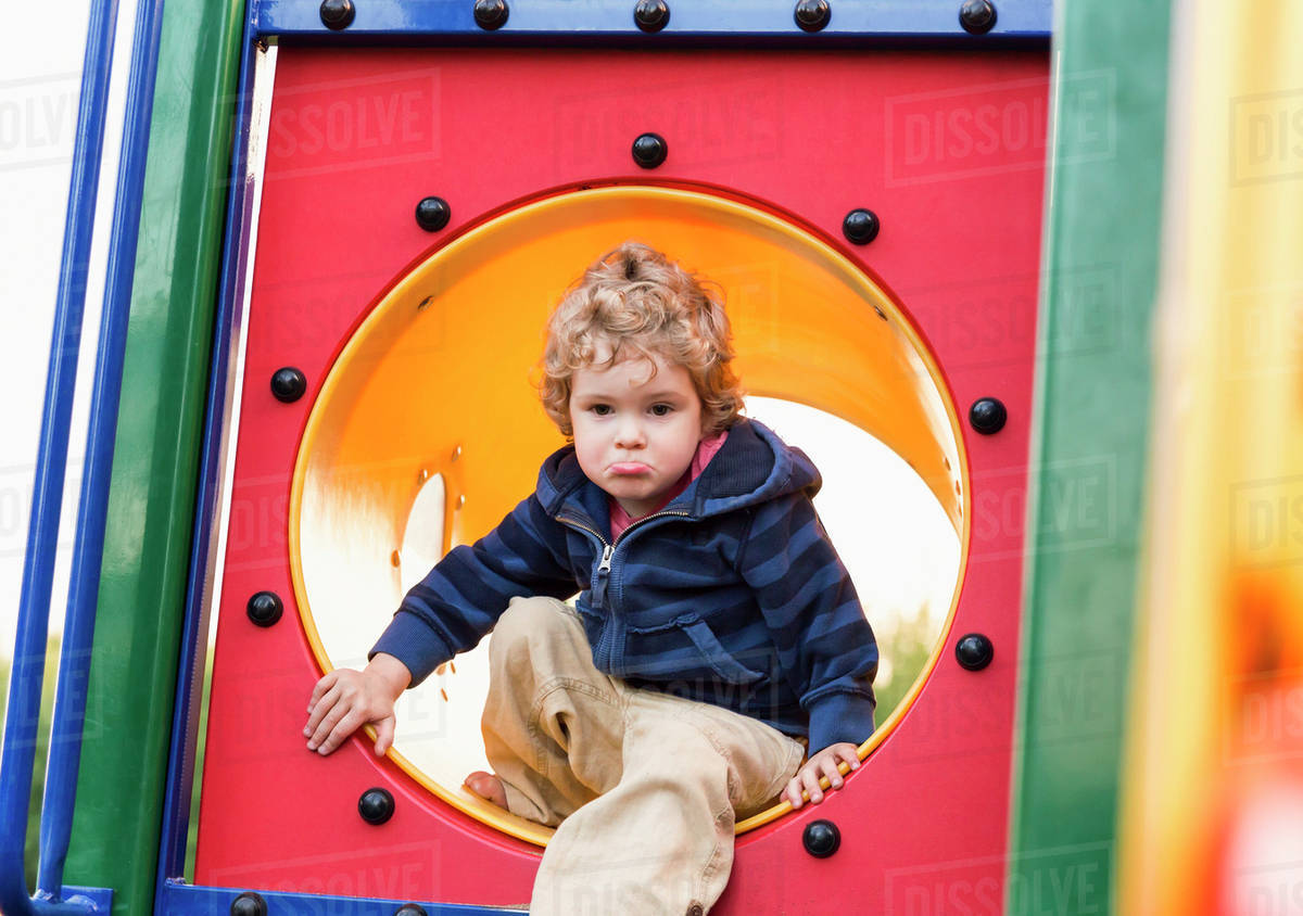 Toddler boy playing by himself at a city playground at sunset; St ...