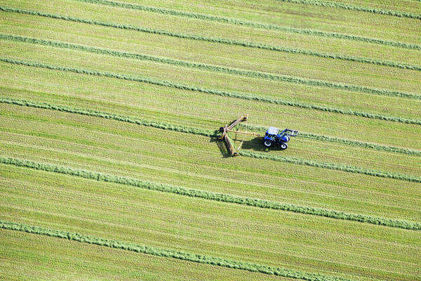 Aerial view of a tractor in a hay field working with machinery making ...