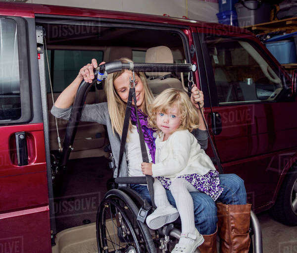 Young disabled mother with her daughter using wheelchair powered device ...