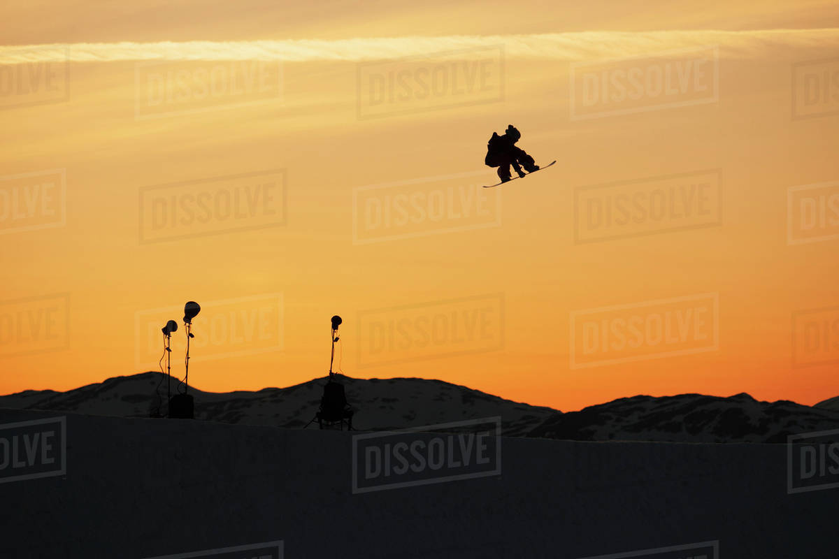 Silhouette of a snowboarder jump in mid-air at sunset; Norway - Royalty ...