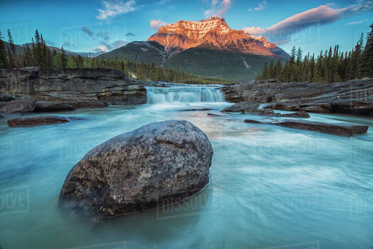 Sunset lights up Mount Fryatt as the Athabasca River flows over ...
