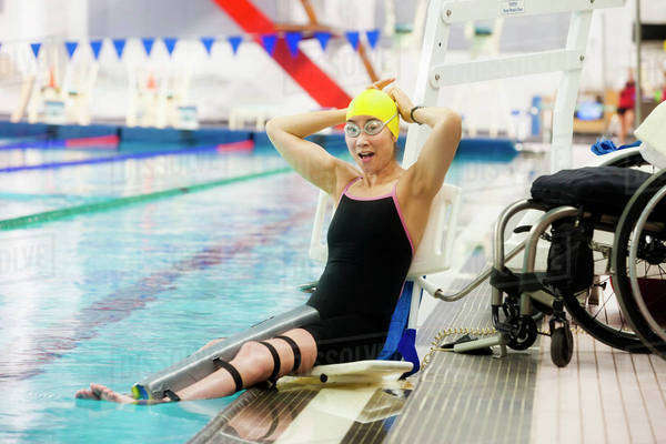 A Paraplegic Woman Sits At The Edge Of A Swimming Pool On A Lift Beside ...