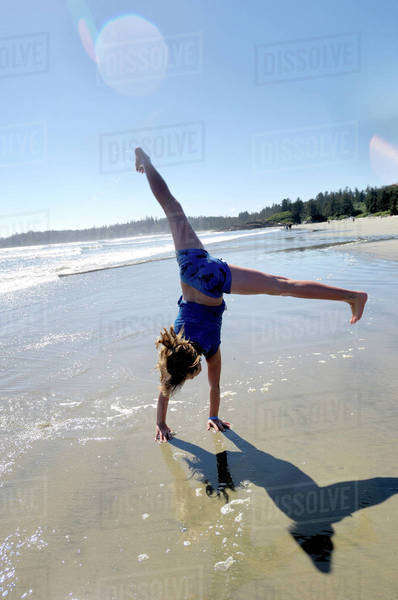 Pre-Teen Girl Performing Cartwheel On Beach, Vancouver Island, Canada ...
