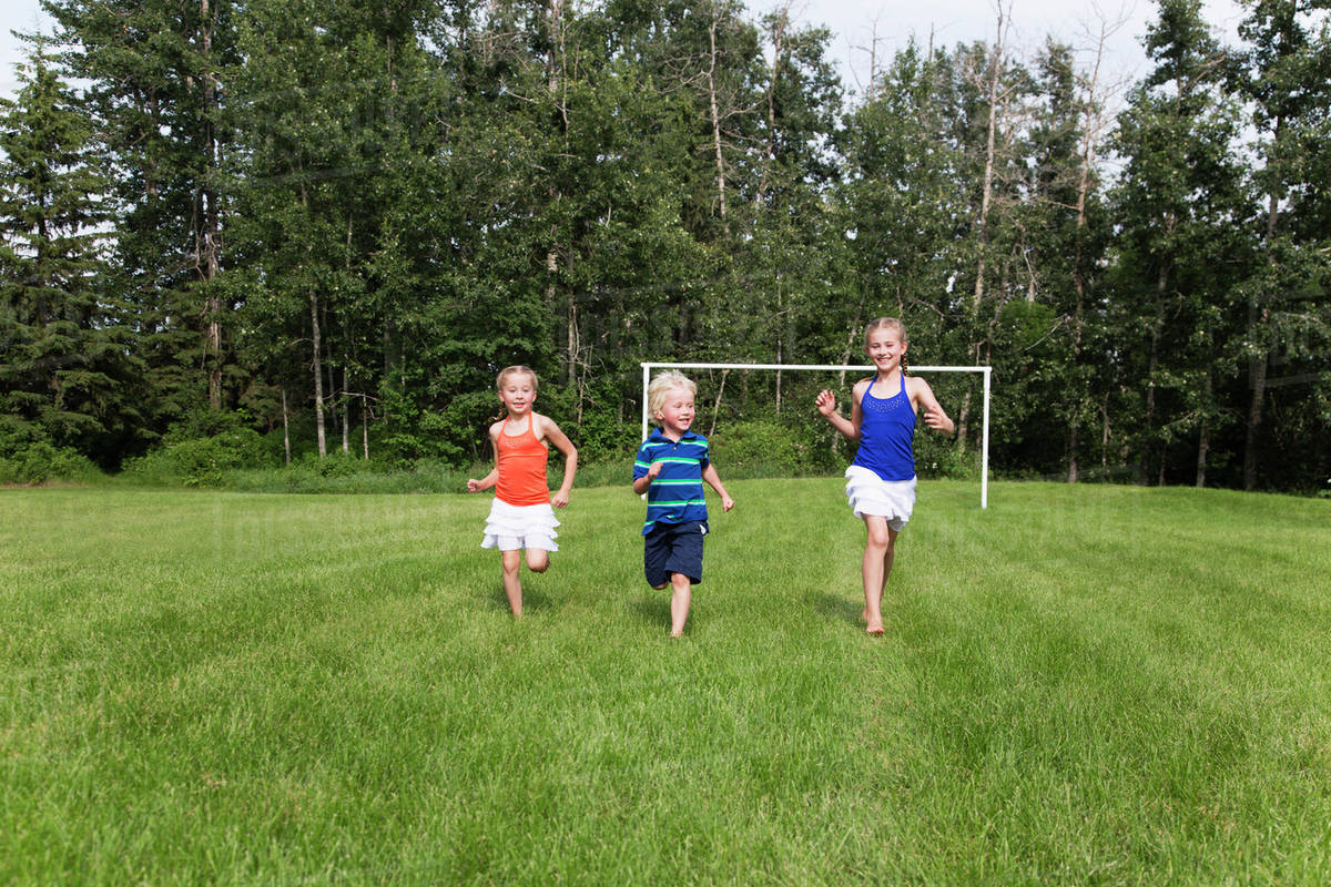 Kids running across a grass field in a park; Stony Plain, Alberta ...