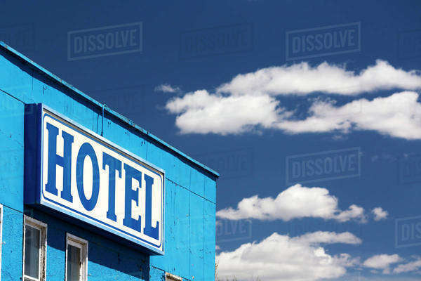 Close up of hotel sign on blue building with blue sky and clouds ...