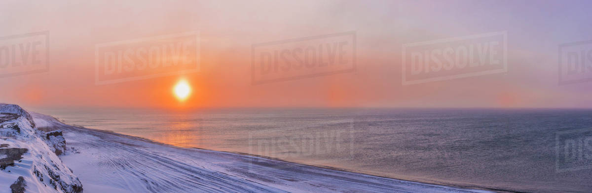 Sunset through windblown snow creates a sundog above the Beaufort Sea ...