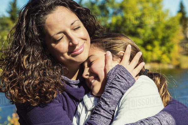 A mom hugging her daughter tightly during a family outing in a city ...