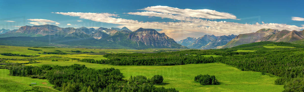 Panorama view of green fields with trees, rolling foothills, mountain ...