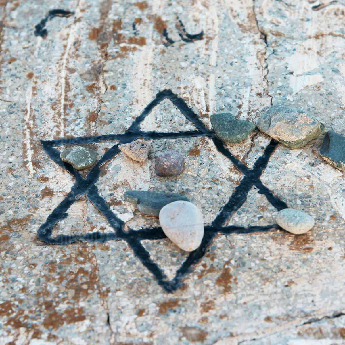 A star of david etched and painted on a rock with stones laying on it ...