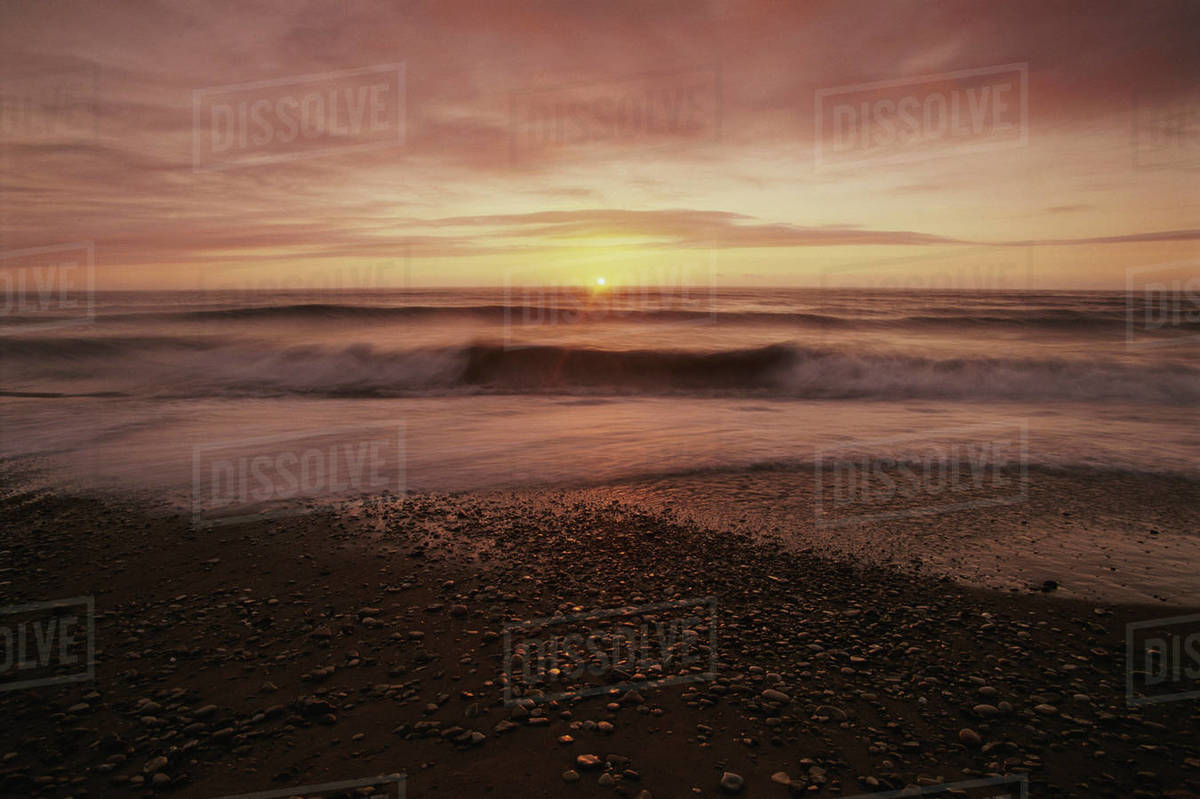 Breaking surf on a Yukon Territory beach of Firth River at sunset ...