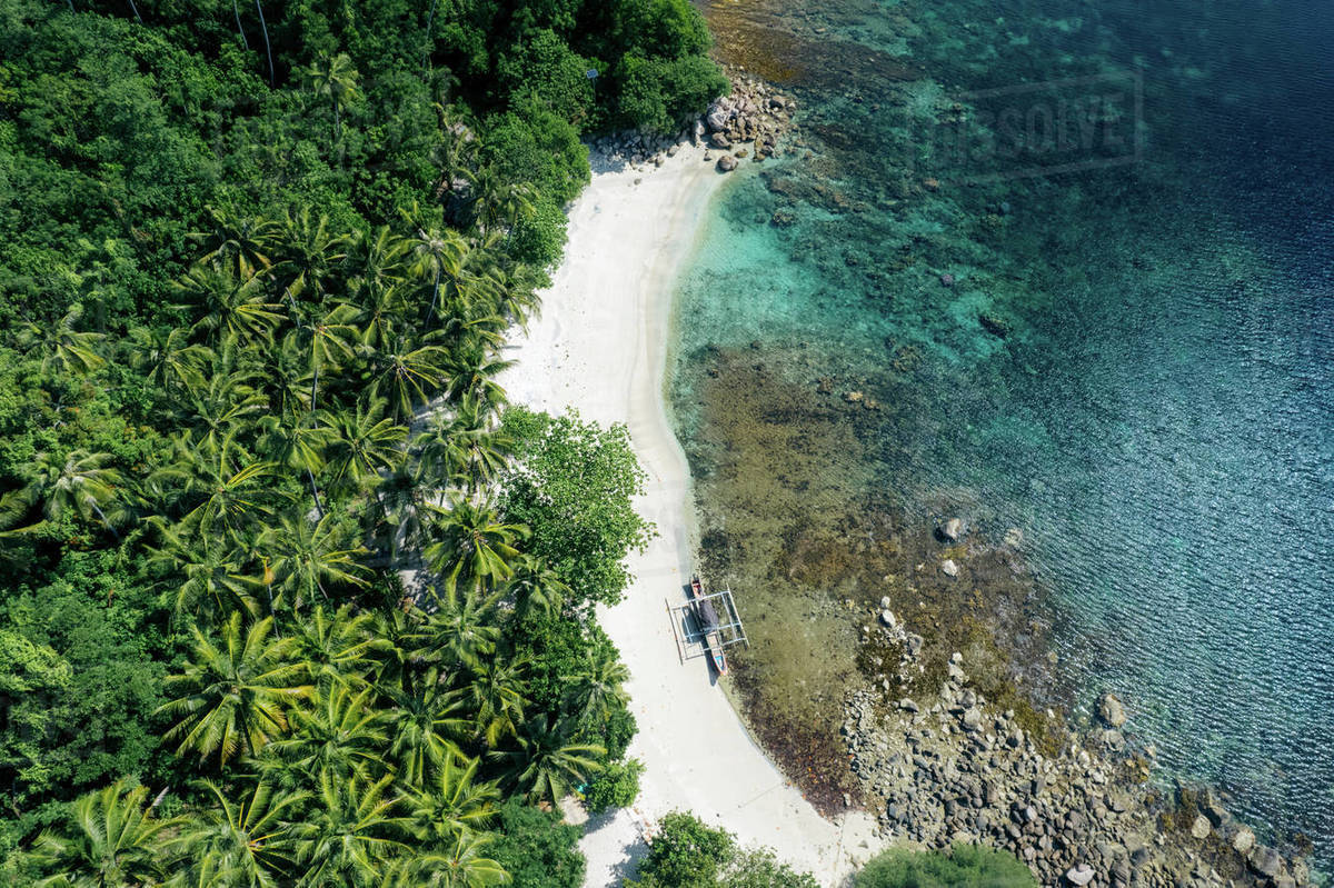 Patokan Beach (Jiko) with a boat on the white sand beach and palm trees ...