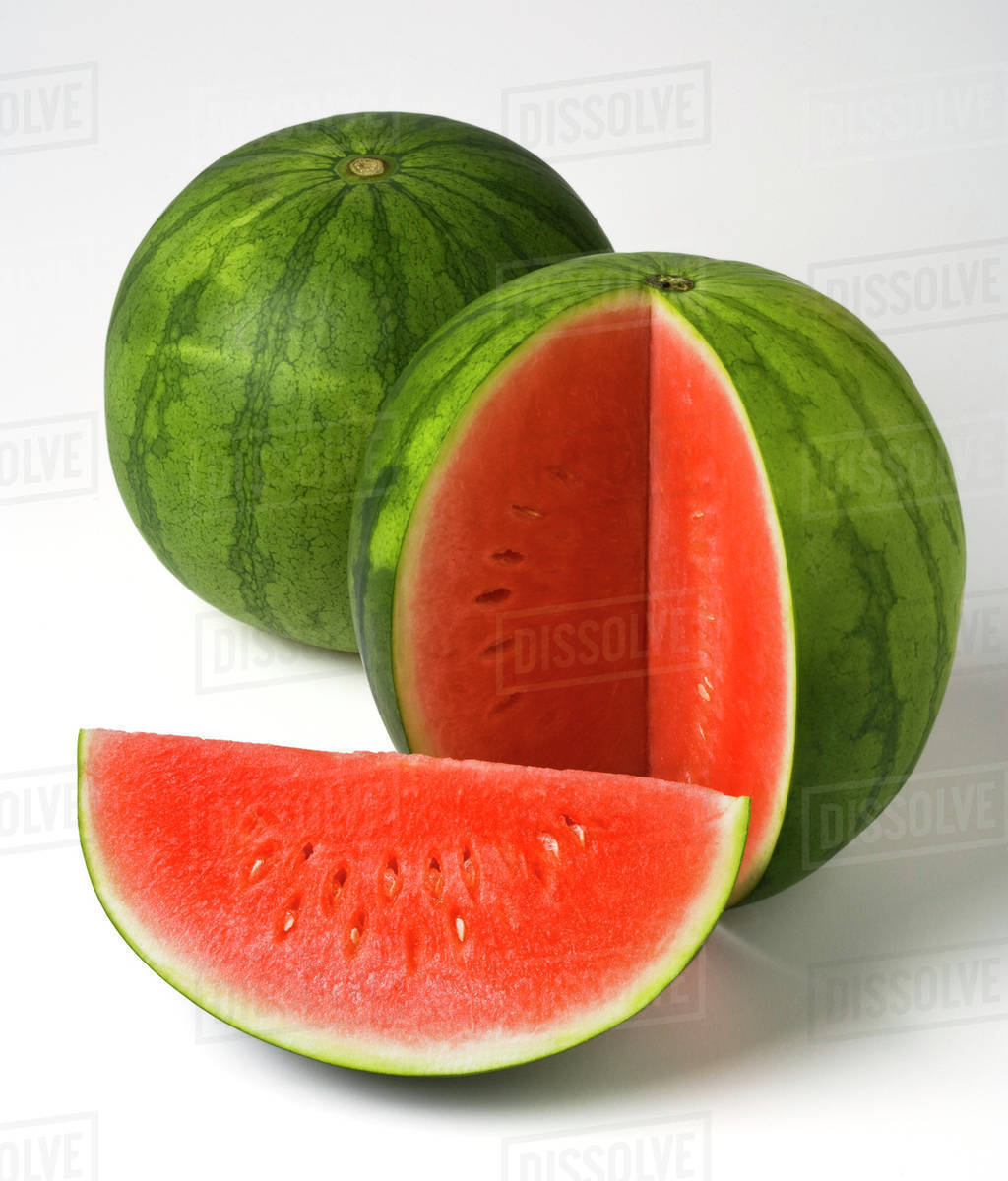 Agriculture - Watermelons, one with a sliced wedge, on a white surface ...