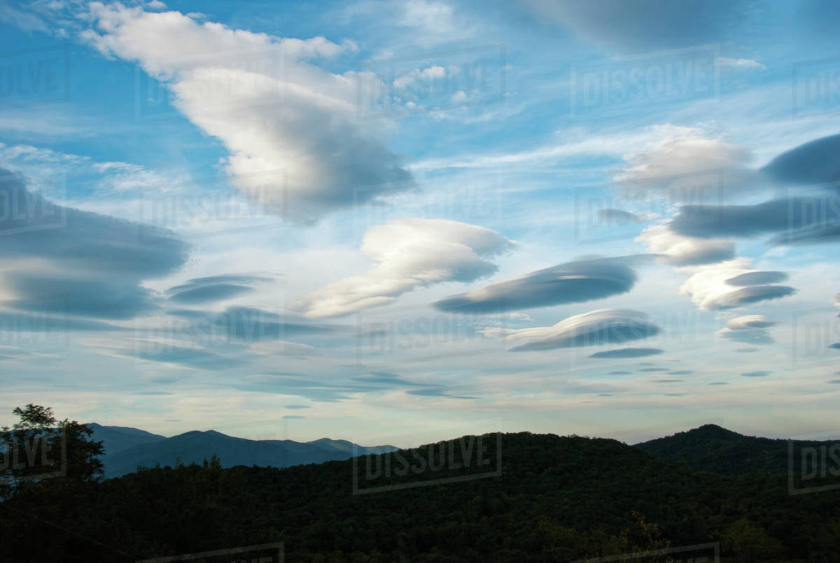 Lenticular clouds form over mountains - Stock Photo - Dissolve