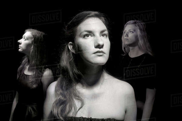 Three young women in formal wear looking upwards against a black ...