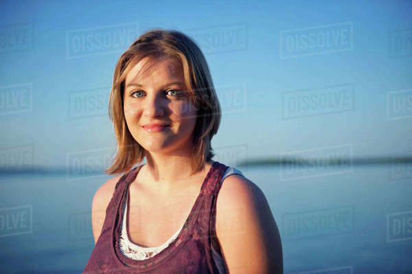 Outdoor portrait of a beautiful teenage girl with a blue lake and sky ...