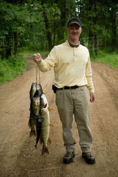 Man holds a stringer of Largemouth bass (Micropterus salmoides) and ...