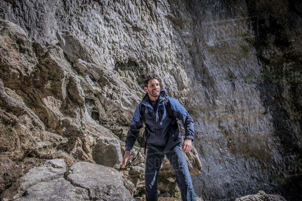 A mountaineer climbing over rocks in rugged terrain. - Royalty-free ...