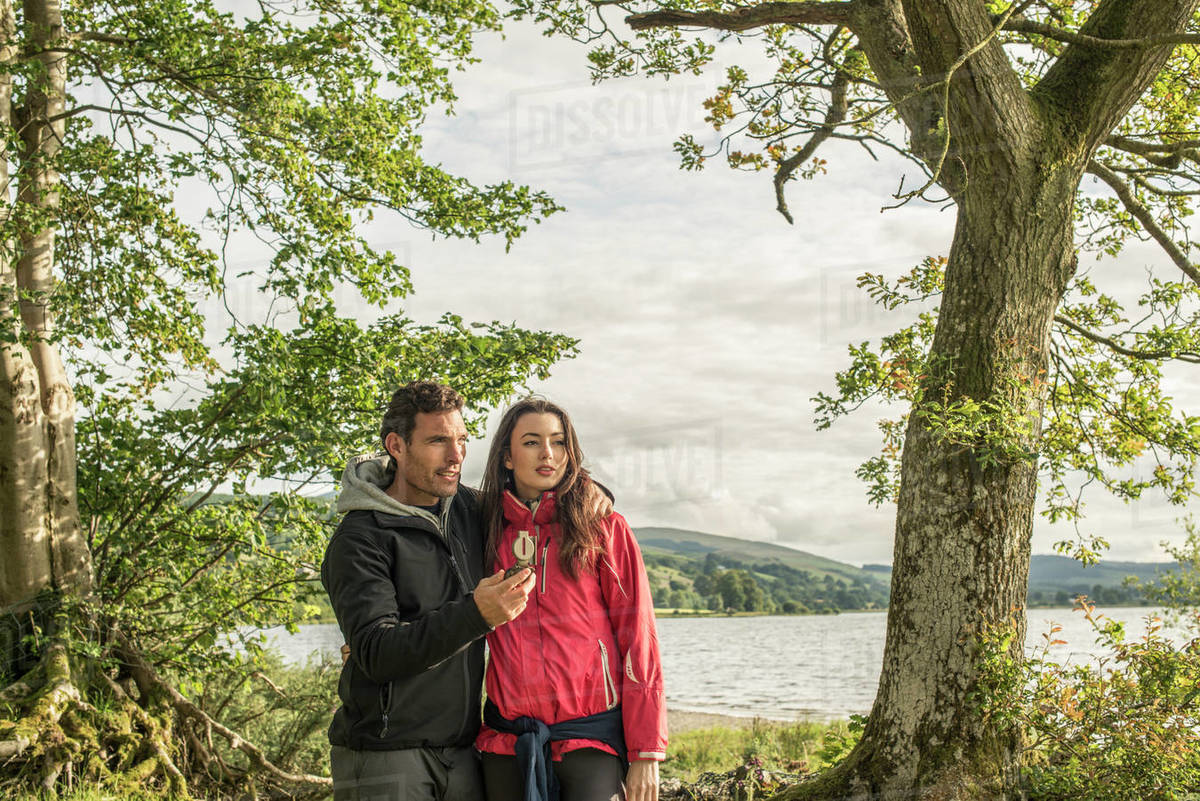 A man and woman using a compass on the shore of Bala Lake in Wales ...