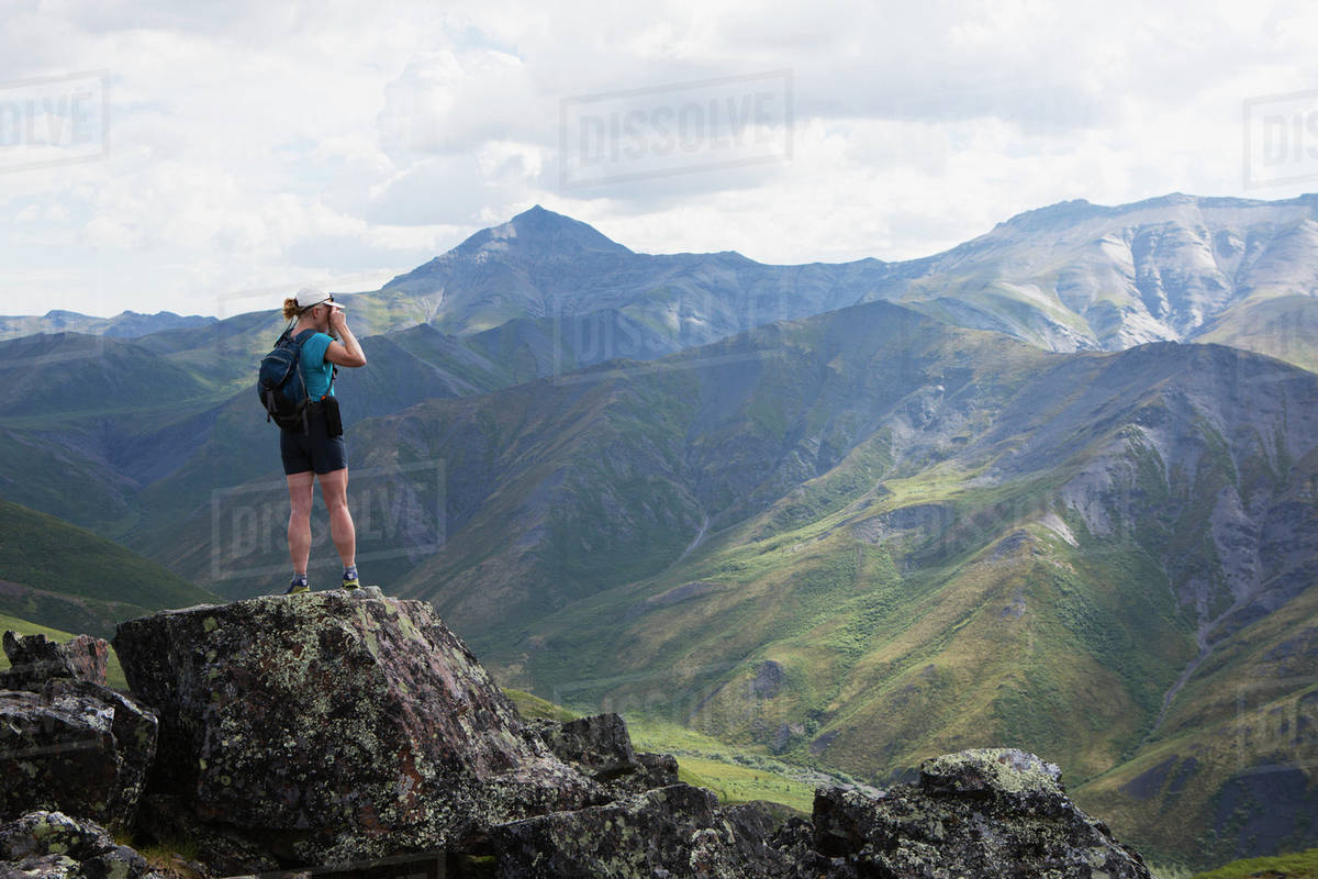A female hiker stands looking over the landscape of mountains and ...