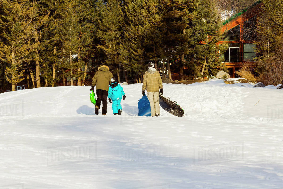 Two Men Walking With A Child After Sledding In A Mountain Resort ...