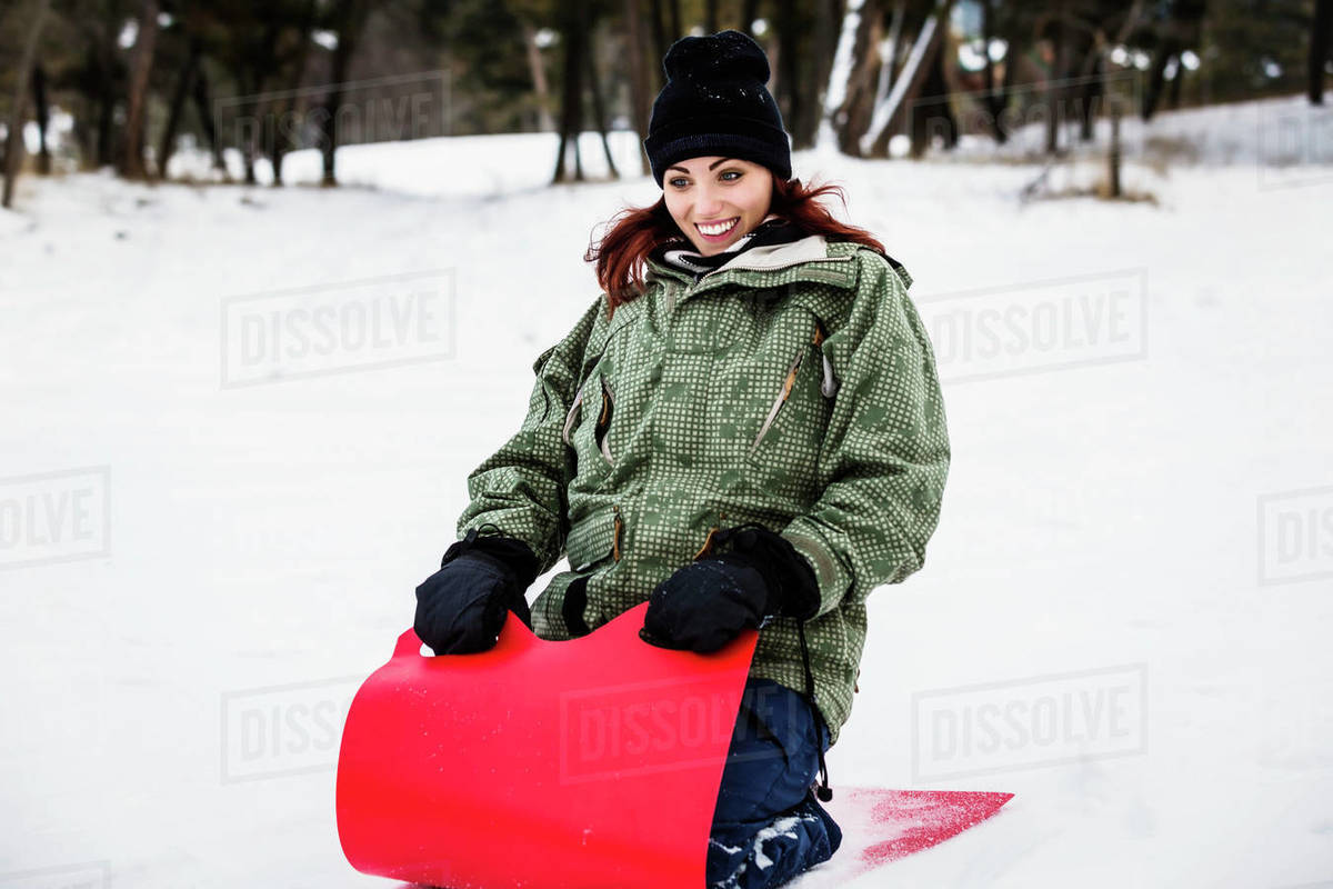 A Woman Has A Big Smile As She Rides A Crazy Carpet Sled Down A Snowy ...