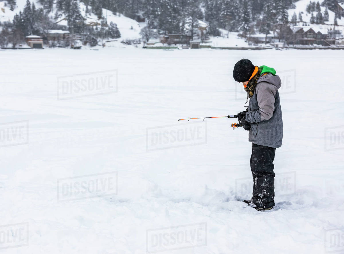 Young boy patiently ice fishing in frozen Windermere Lake, Windermere ...