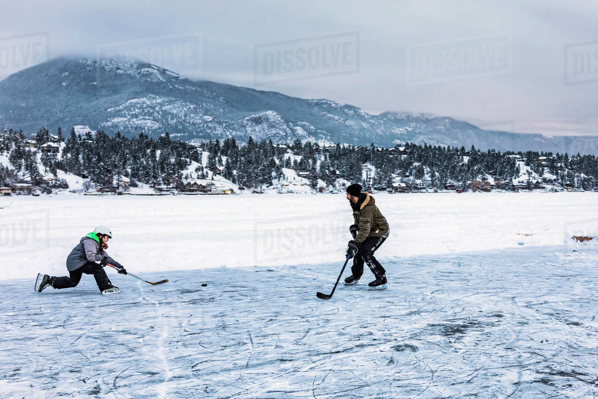 Father and his son playing hockey on a frozen Windermere Lake during ...