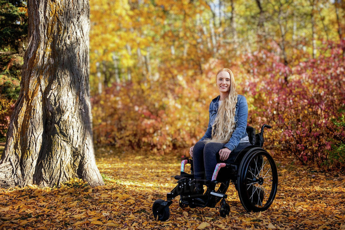 A young paraplegic woman in her wheelchair in a park on a beautiful ...
