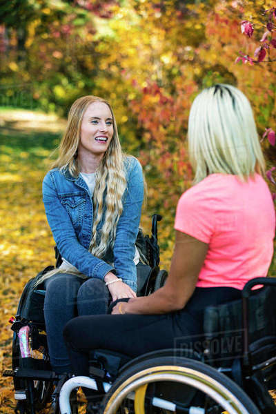 Two young women paraplegics in their wheelchairs visiting together in a ...
