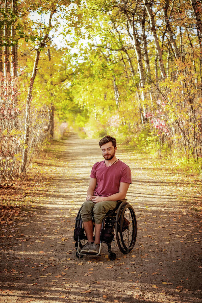 Portrait of a paraplegic man in a wheelchair outdoors in a park in ...