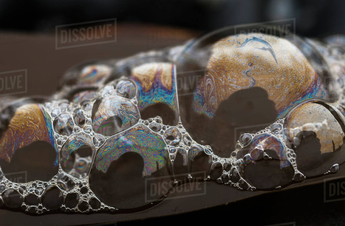 Sea foam creates colourful patterns and reflections; Cannon Beach ...