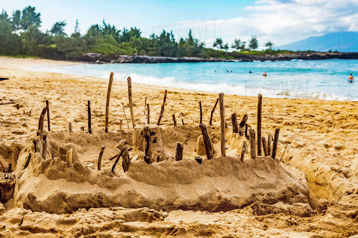 A sandcastle with sticks around the edges on the shore of D. T. Fleming ...