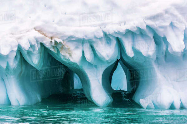 Blue ice tunnels form from an ice formation at the water's edge ...