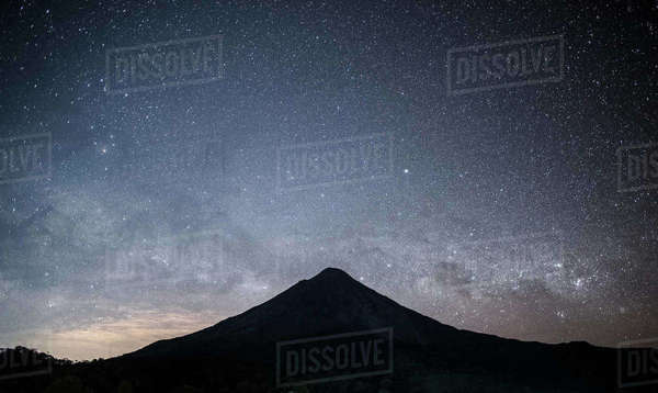 The Milky Way galaxy rises above a dramatic silhouette of the Arenal ...