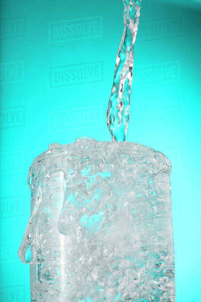 Water Pouring Into Overflowing Glass - Stock Photo - Dissolve