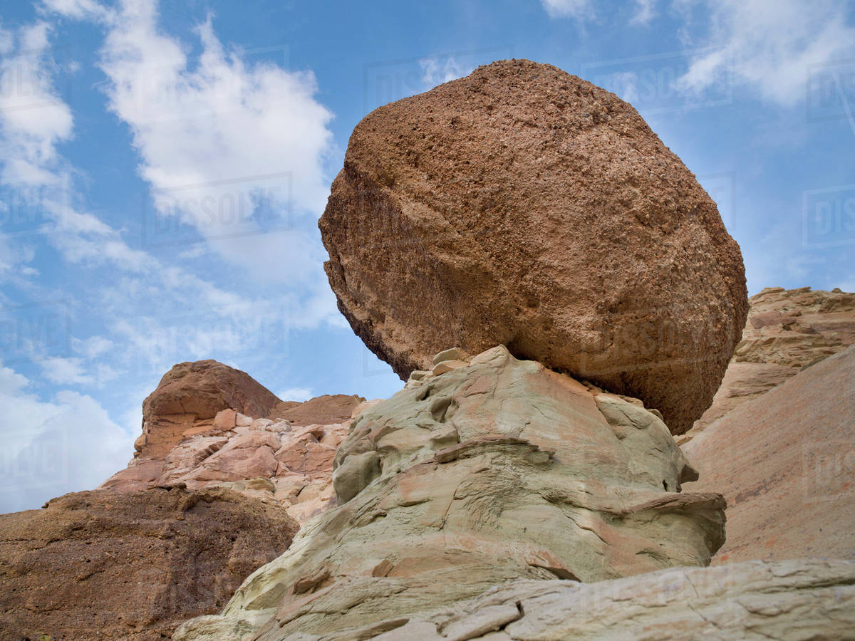 A Large Boulder Resting On A Rock Formation On Rugged Terrain; Utah ...