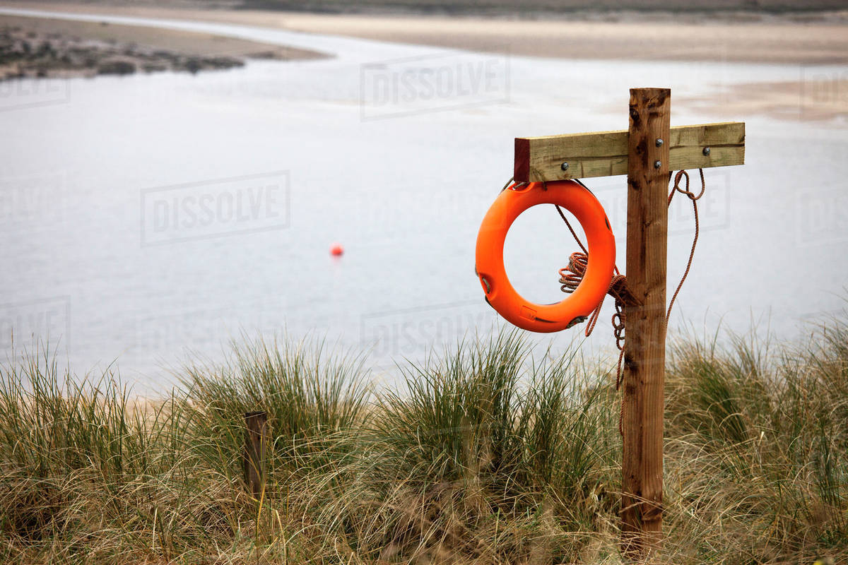 An Orange Life Preserver Hangs On A Wooden Structure At The Water's ...