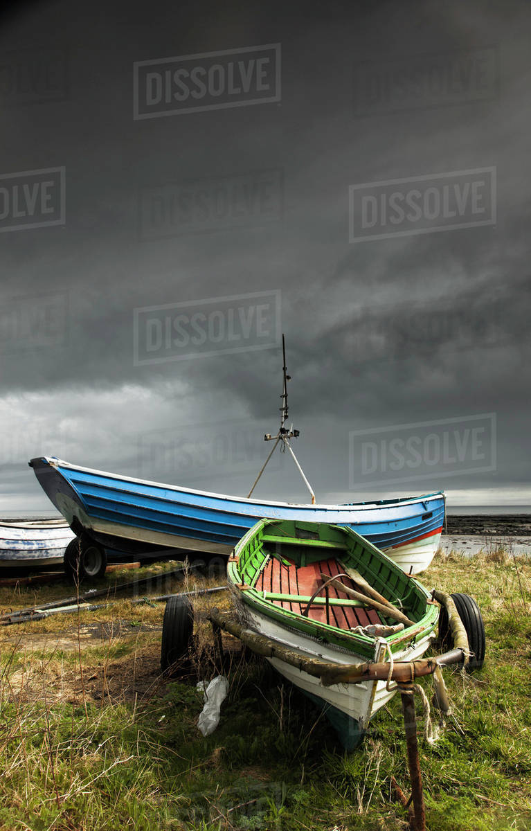 Rowboats sitting on trailers on the shore under storm clouds;Boulmer ...