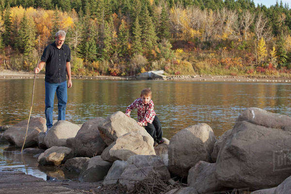Grandfather And Grandson Playing Along The Rocks At The River's Edge ...