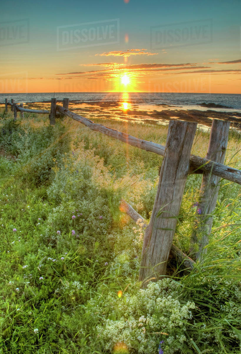 Sunset Over Water And A Fence Along The Shoreline; La Martre, Quebec ...